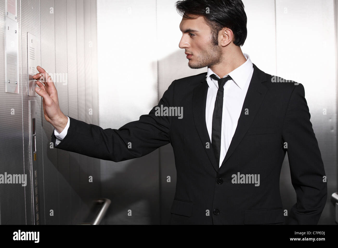 Businessman standing with arms pushing up against balcony overlooking ...