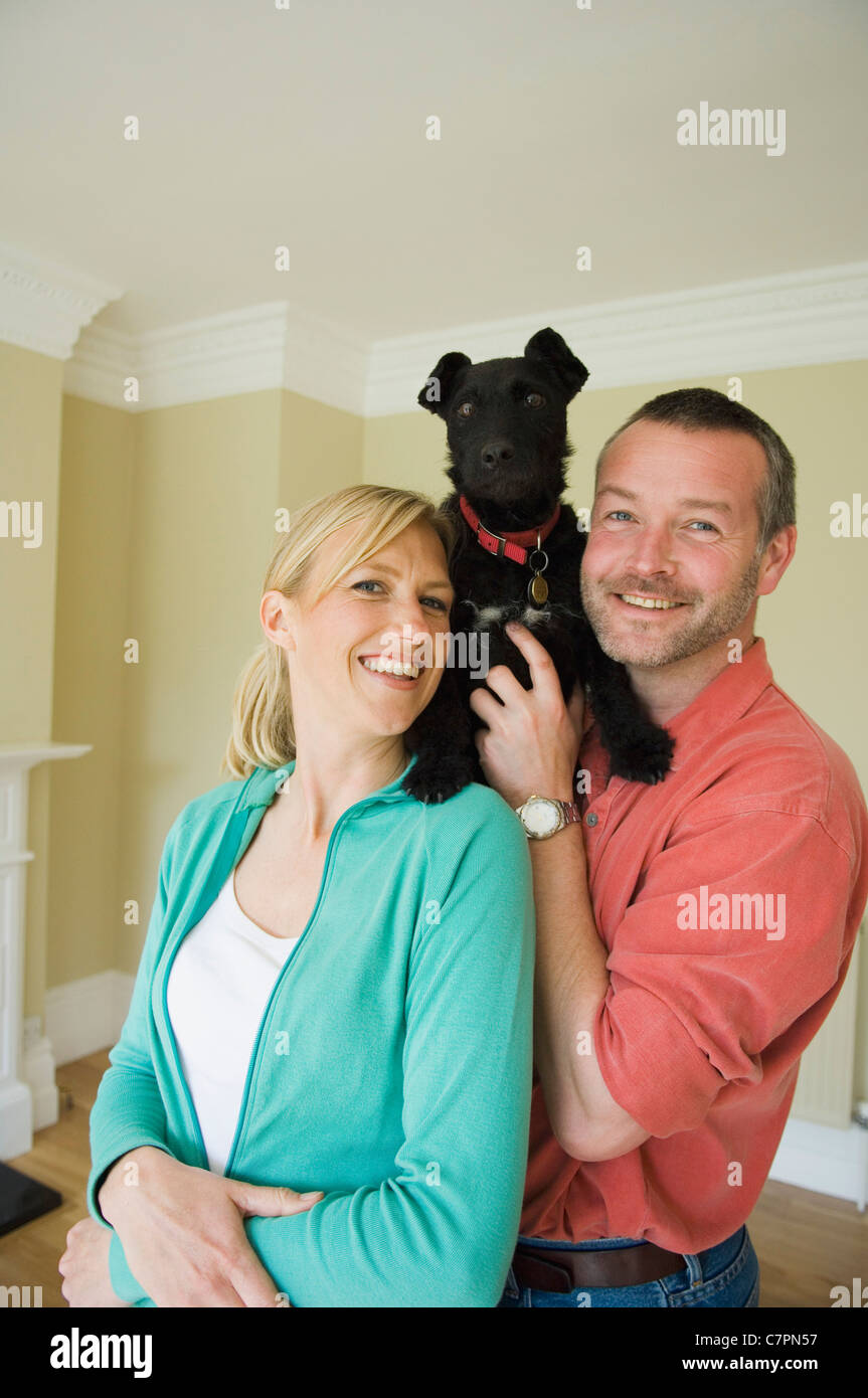 Smiling couple with dog in new home Stock Photo - Alamy