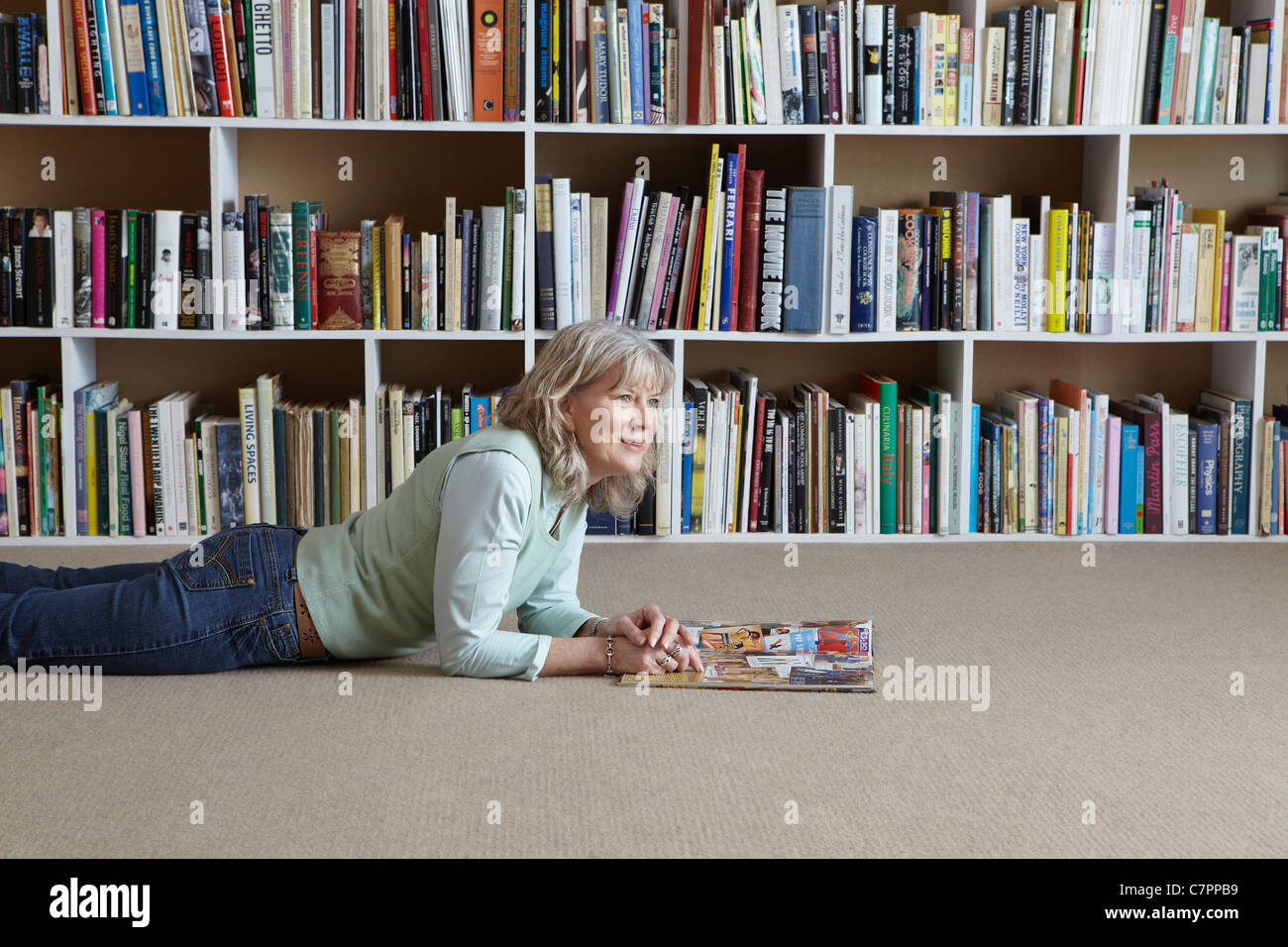 Older woman reading by bookshelves Stock Photo - Alamy