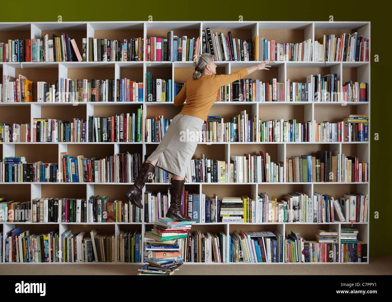 Older woman standing on stack of books Stock Photo - Alamy