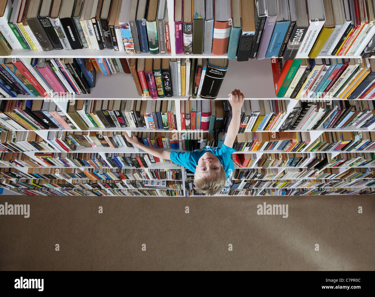 Boy climbing bookshelves Stock Photo - Alamy