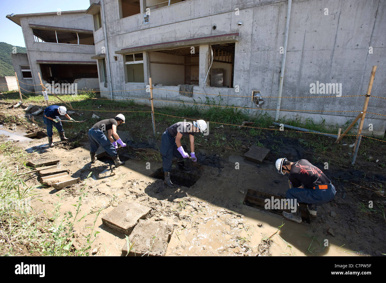 Police dig mud from the drains in search of human remains outside Okawa ...