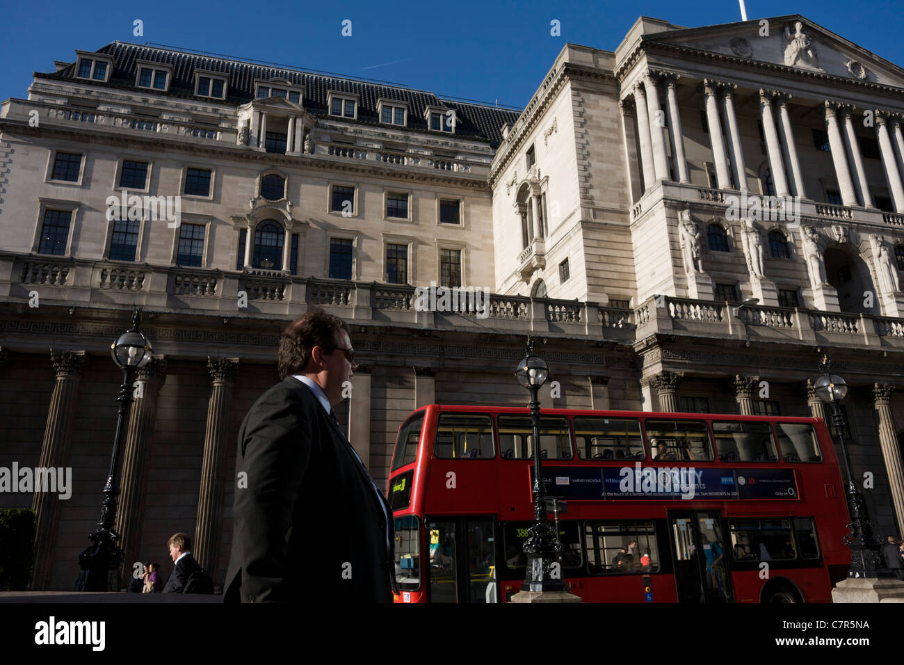 A businessman and red London bus beneath the Bank of England in Bank ...