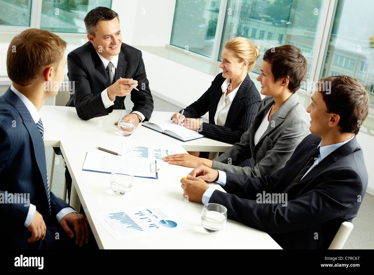 Image of confident colleagues communicating with their boss at meeting ...