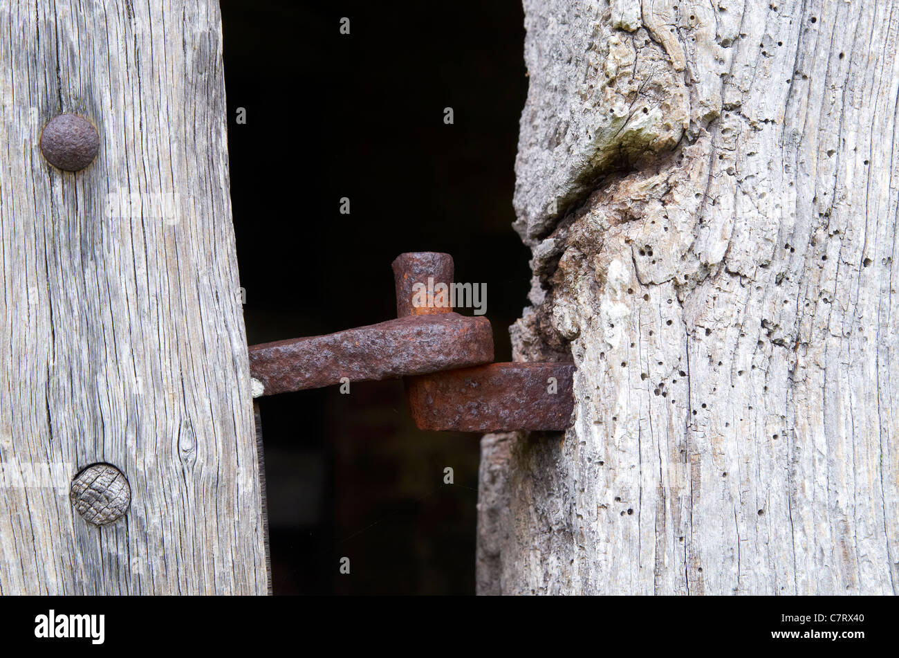 Old simple iron hinge with worm eaten gatepost Stock Photo - Alamy