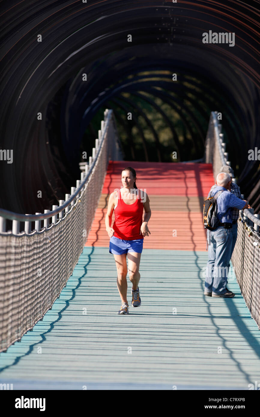 Female jogger, runner, on a pedestrian bridge. Bridge called "Slinky ...