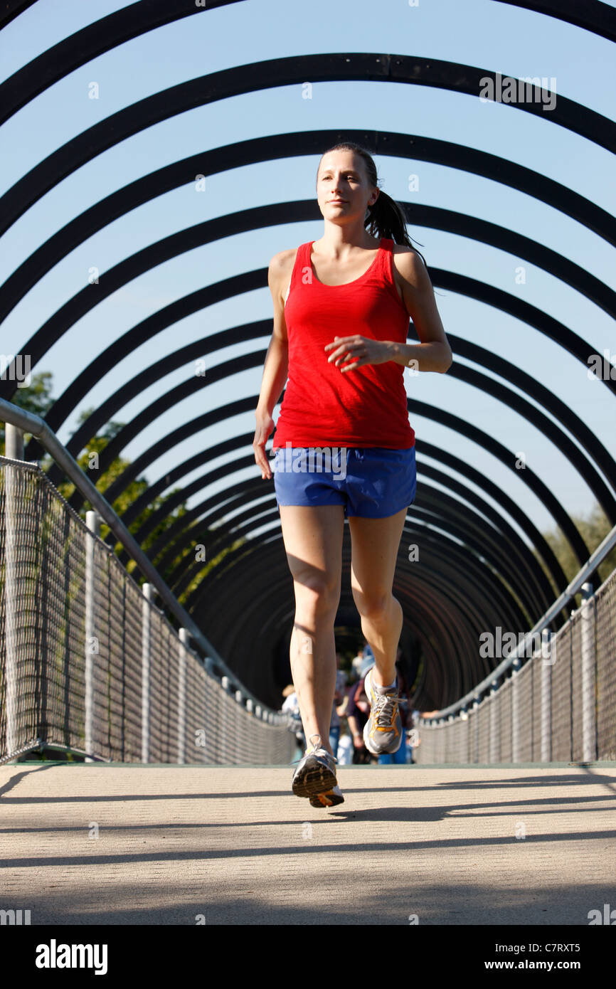Female jogger, runner, on a pedestrian bridge. Bridge called "Slinky ...