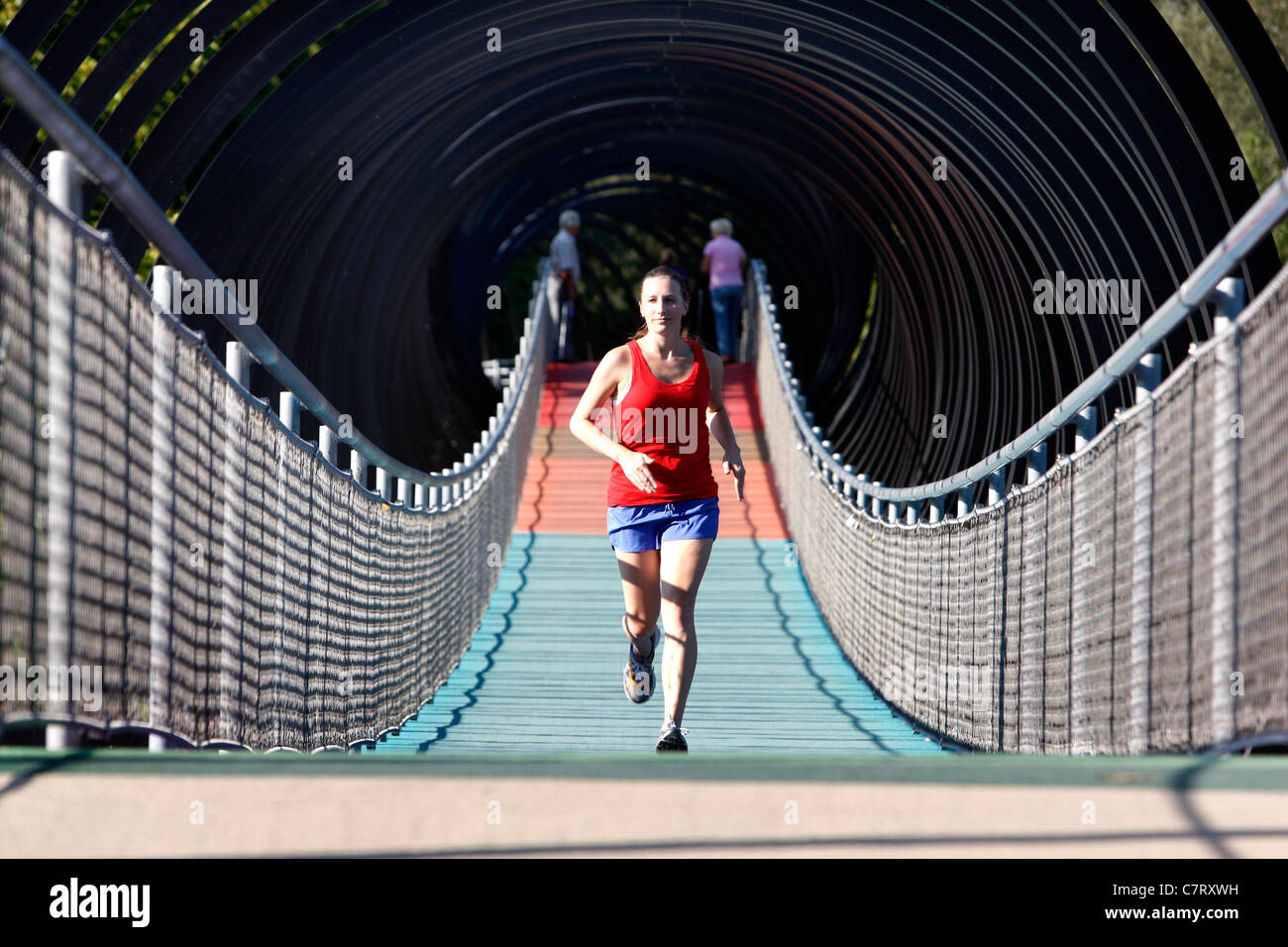 Female jogger, runner, on a pedestrian bridge. Bridge called "Slinky ...