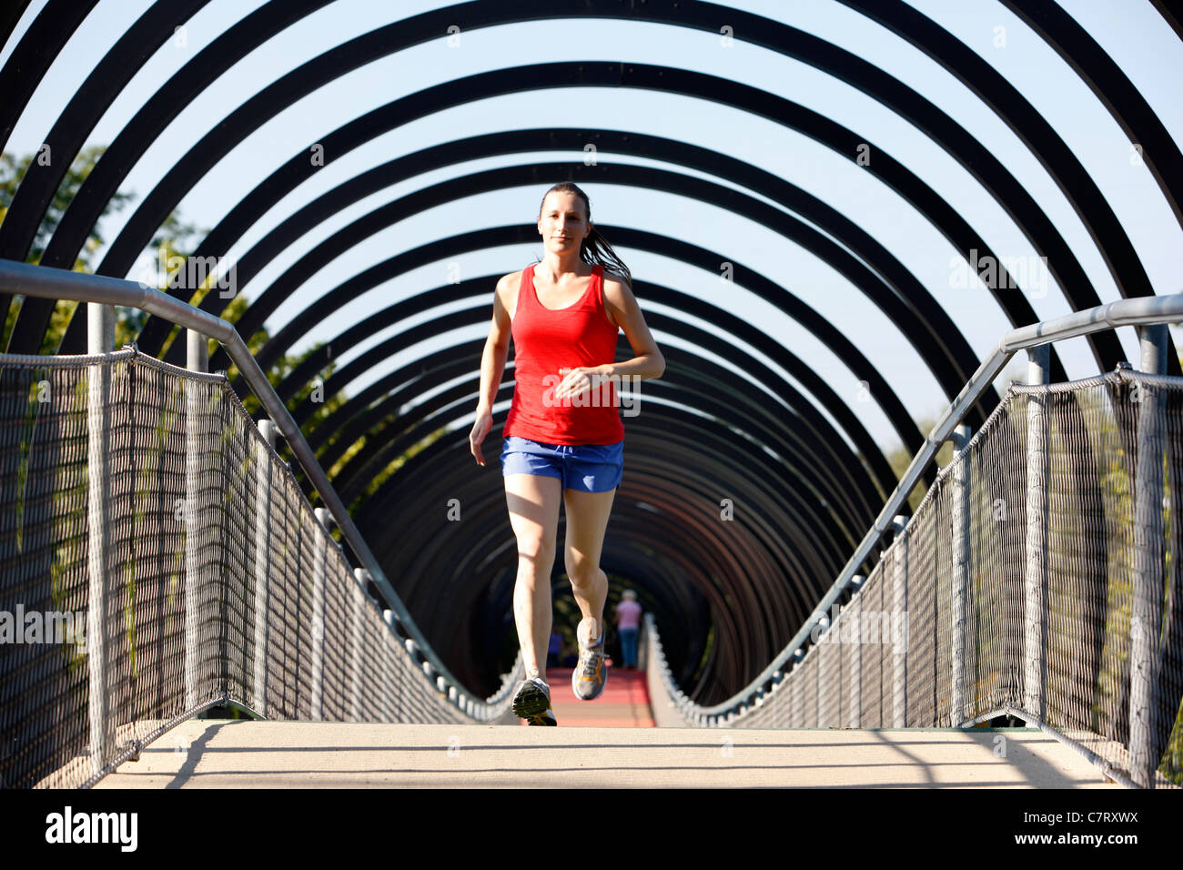 Female jogger, runner, on a pedestrian bridge. Bridge called "Slinky ...