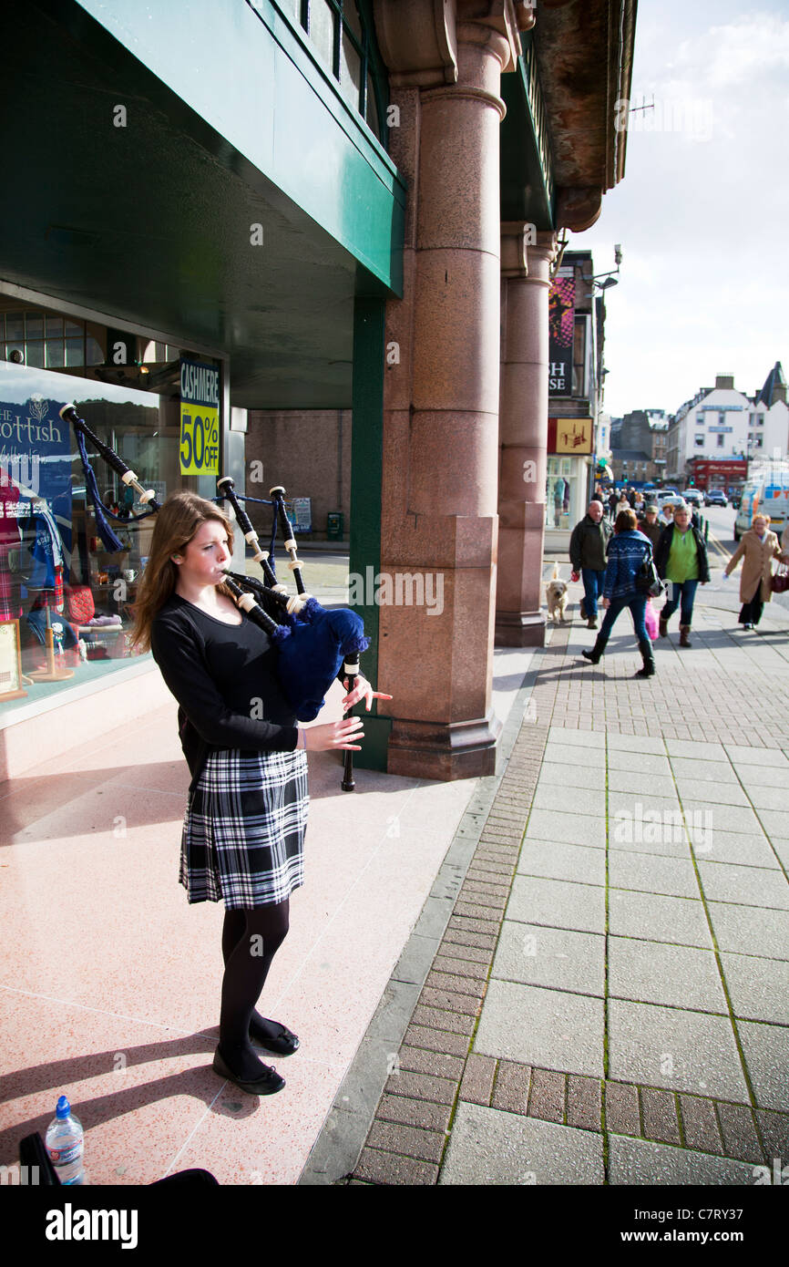 Young girl bagpiper playing bagpipes on street outside in Oban ...