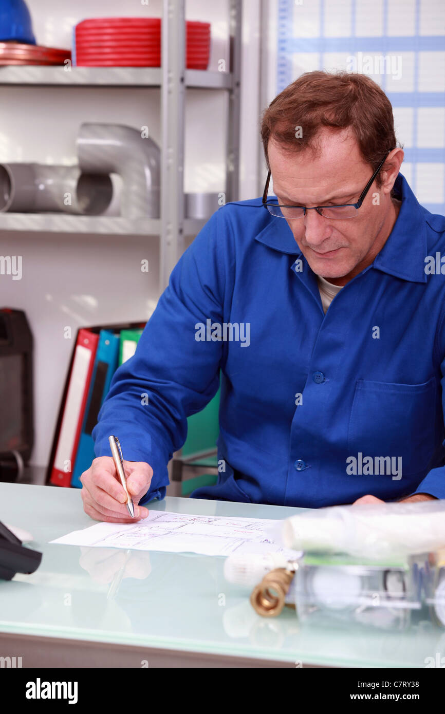 Plumber sat at desk Stock Photo - Alamy
