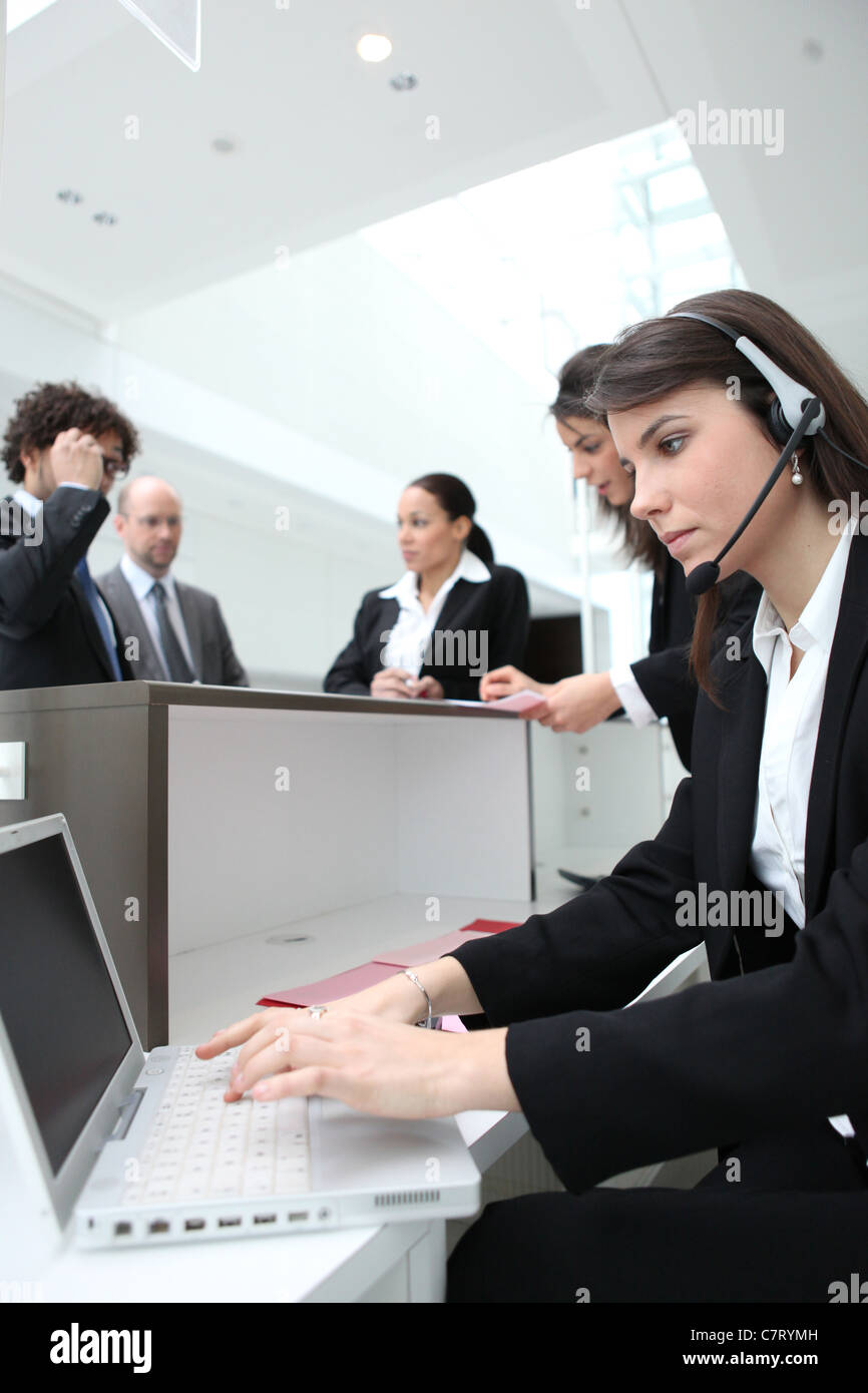 Woman working on a busy reception desk Stock Photo - Alamy