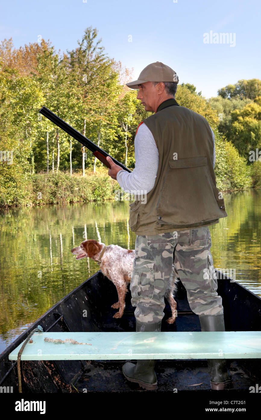 Hunter on boat with dog Stock Photo - Alamy