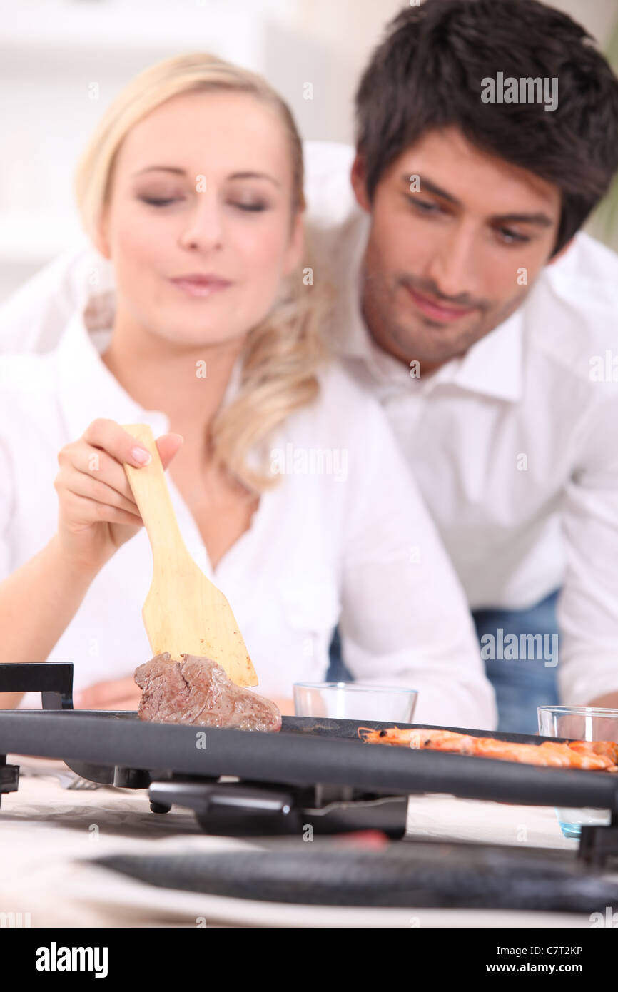Couple cooking surf and turf on a tabletop hotplate Stock Photo - Alamy