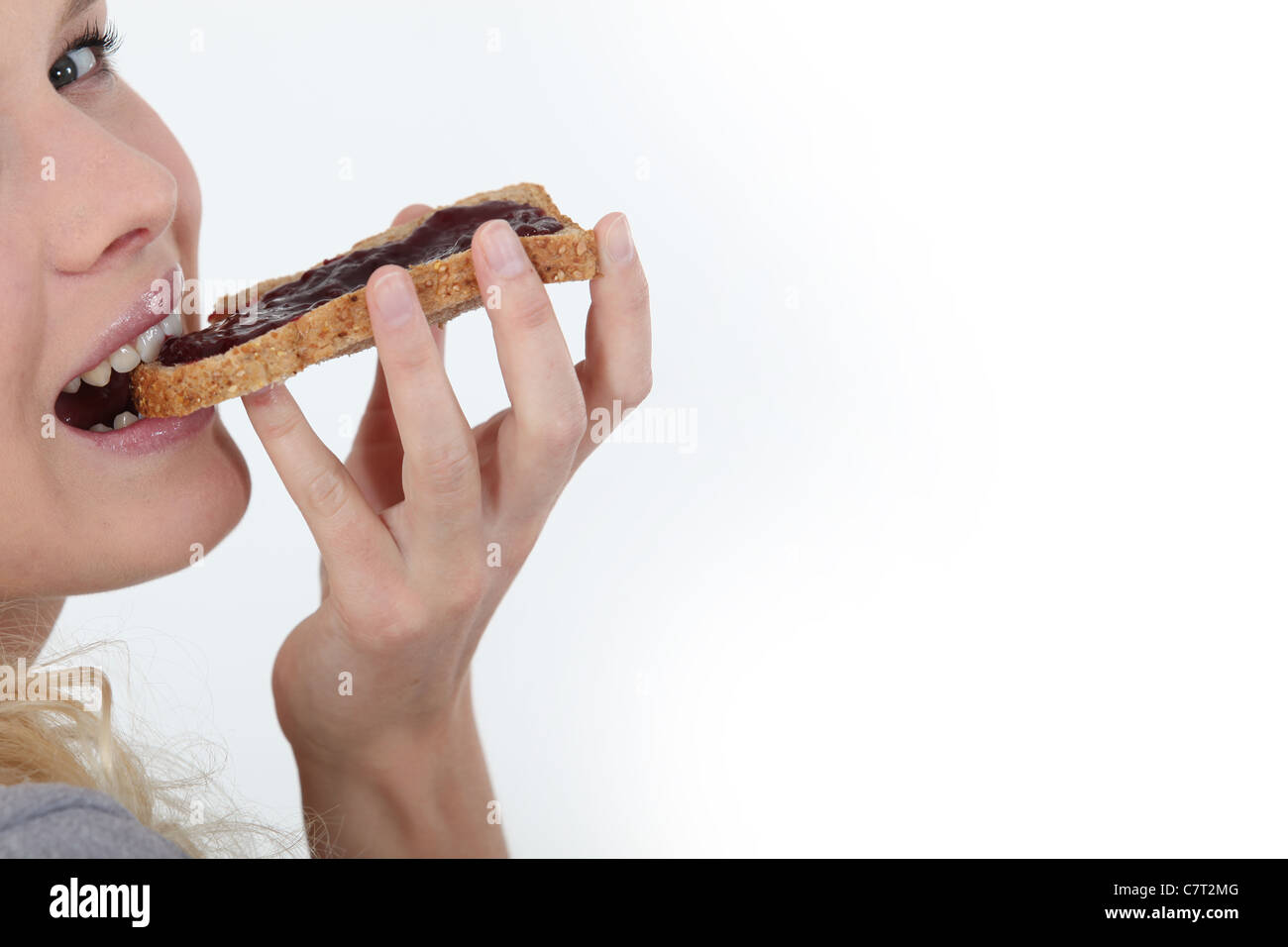 Woman eating jam on toast Stock Photo - Alamy
