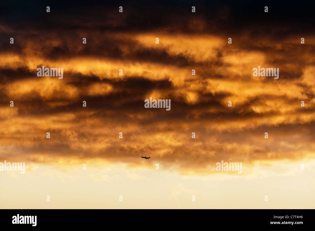 Small regional jet airliner set against a big colorful sunset sky ...