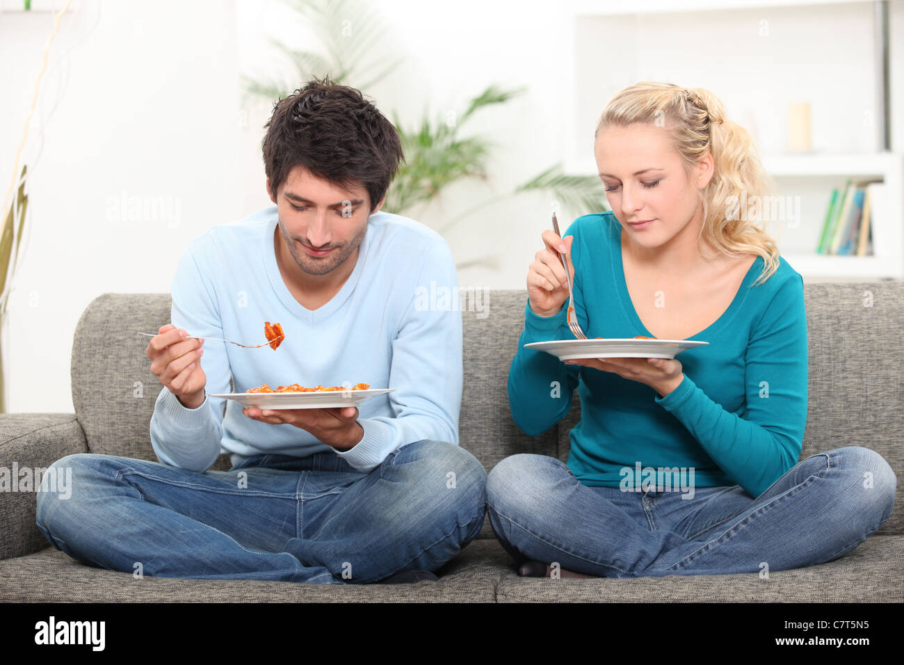 Couple eating diner on a sofa Stock Photo - Alamy