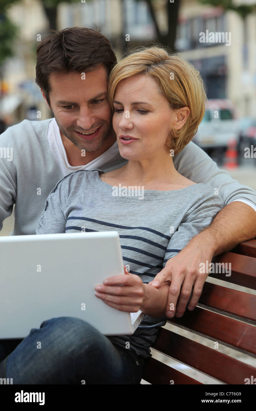 Couple on laptop on bench Stock Photo - Alamy