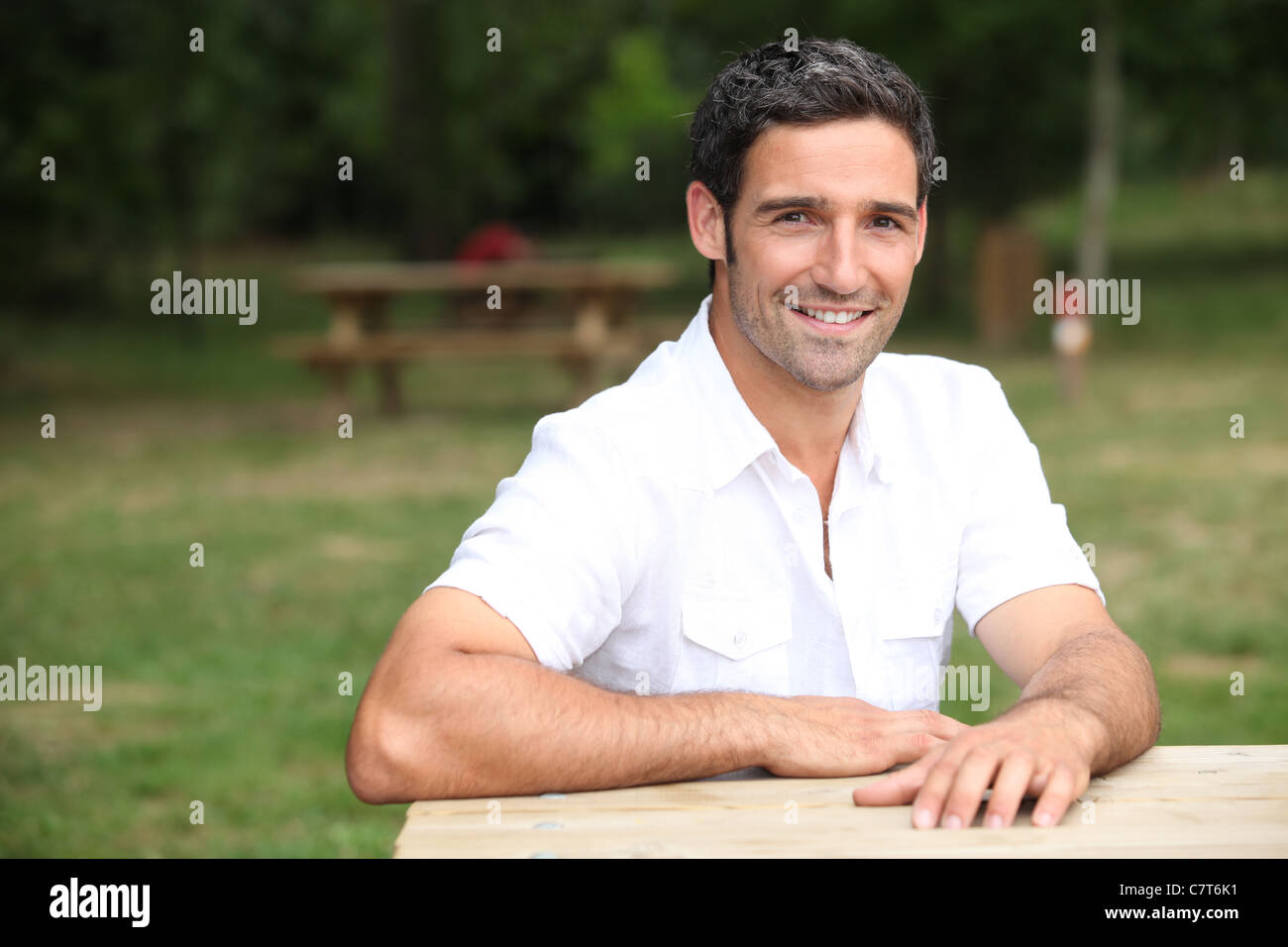 Smiling man at a park bench Stock Photo - Alamy