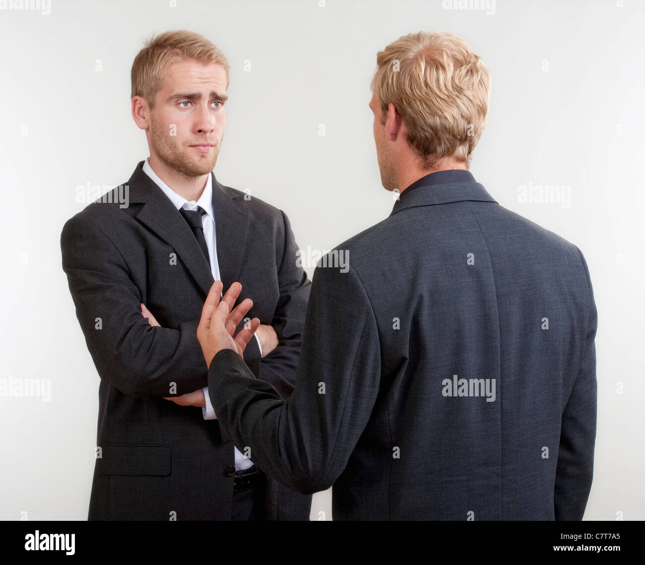 two young businessmen standing, discussing, arguing - isolated on light ...