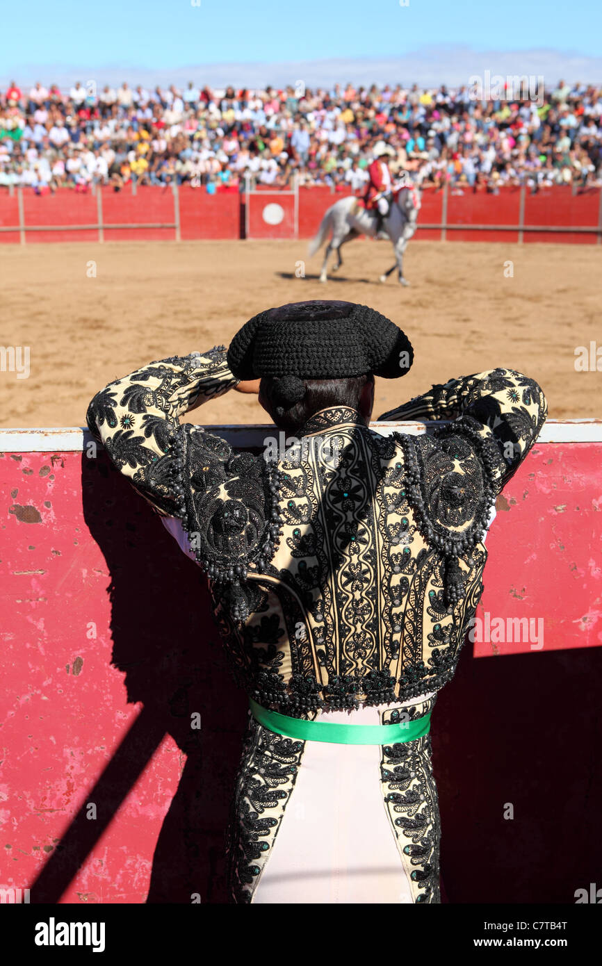 A bullfighter (Bandarilheiro) watches a bullfight from behind the ...