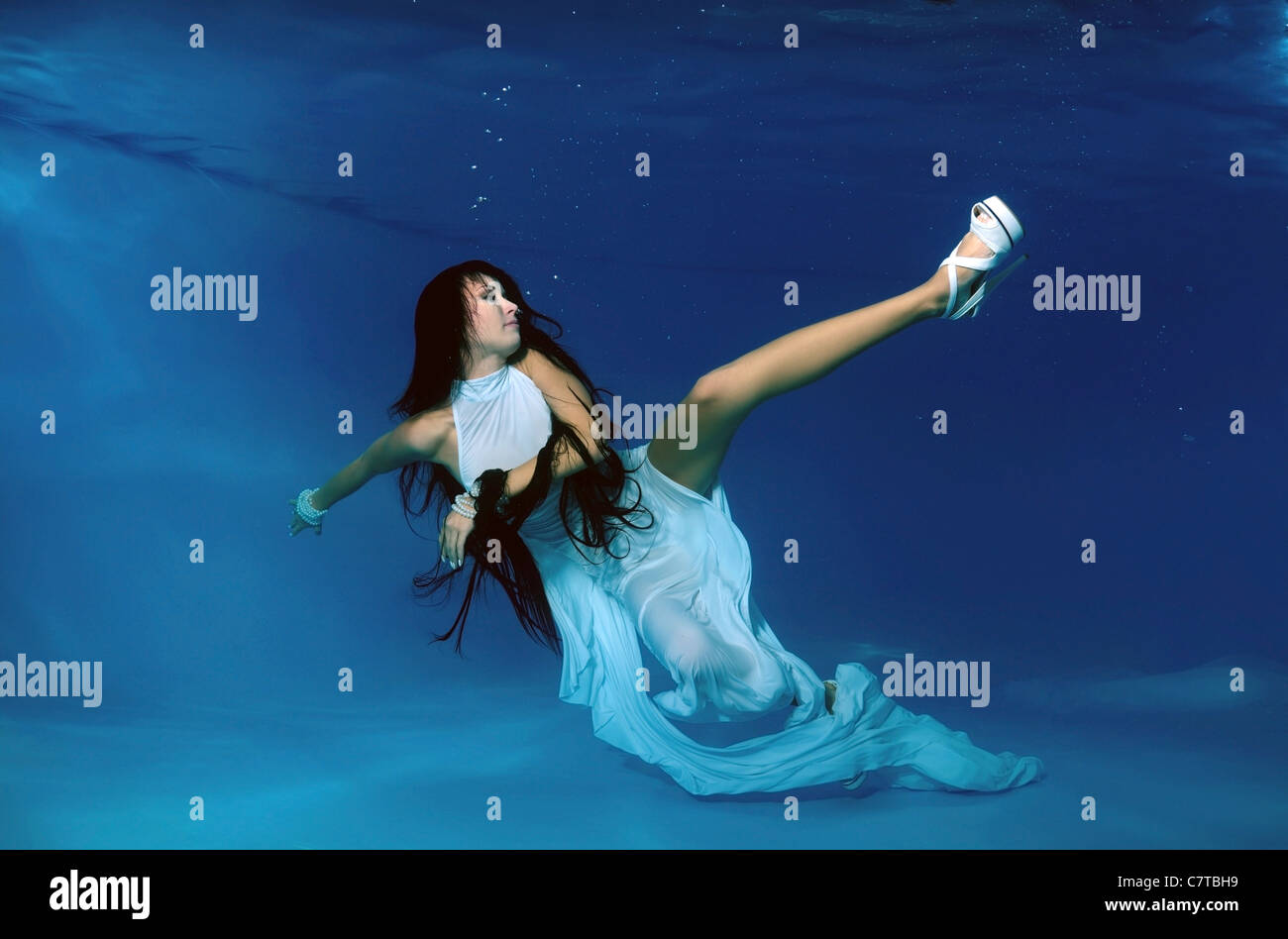 A young woman with big hair posing in a pool underwater Stock Photo - Alamy