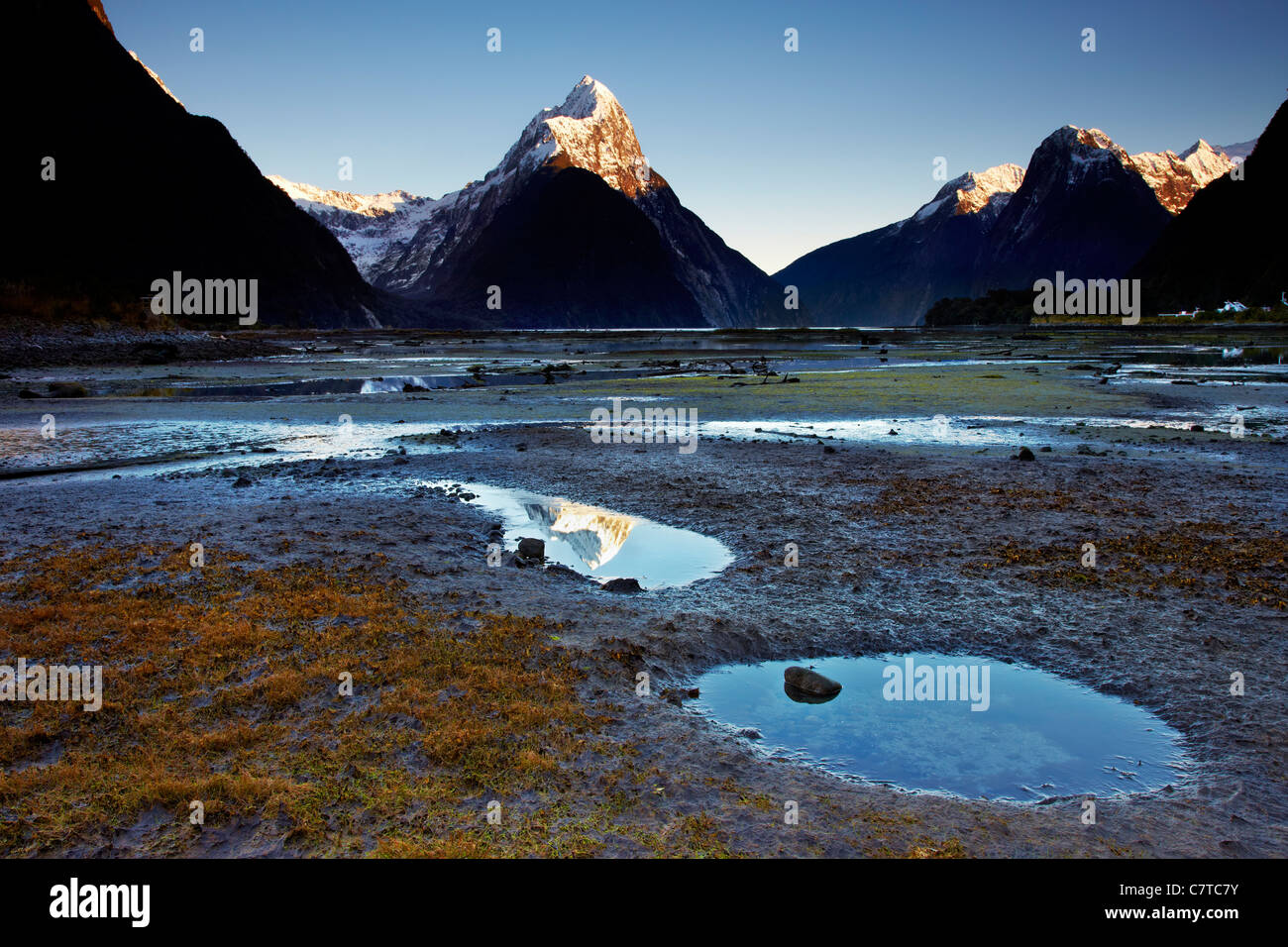 The famous Mitre Peak reflected in the puddles left from the low tide ...