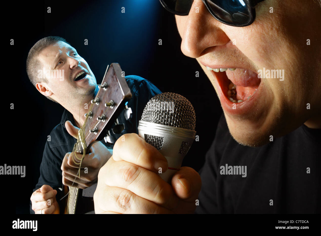 Two performers with microphone and guitar over black background Stock ...