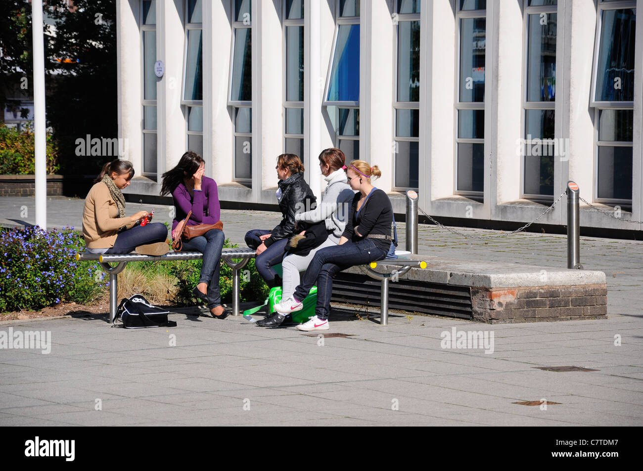 Group of young women sitting on benches outside building Stock Photo ...
