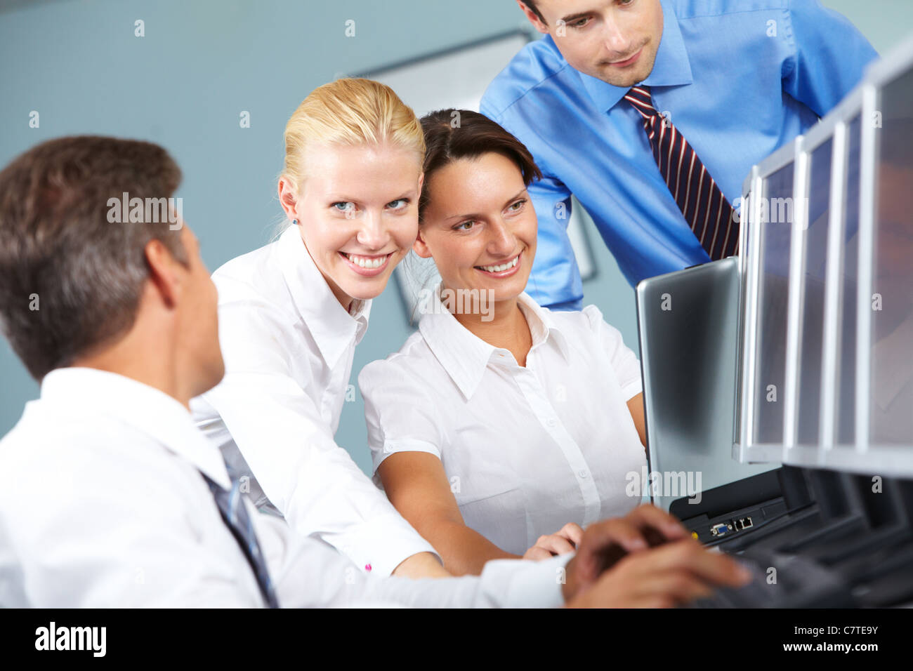 Group of four business people watching computer presentation together ...
