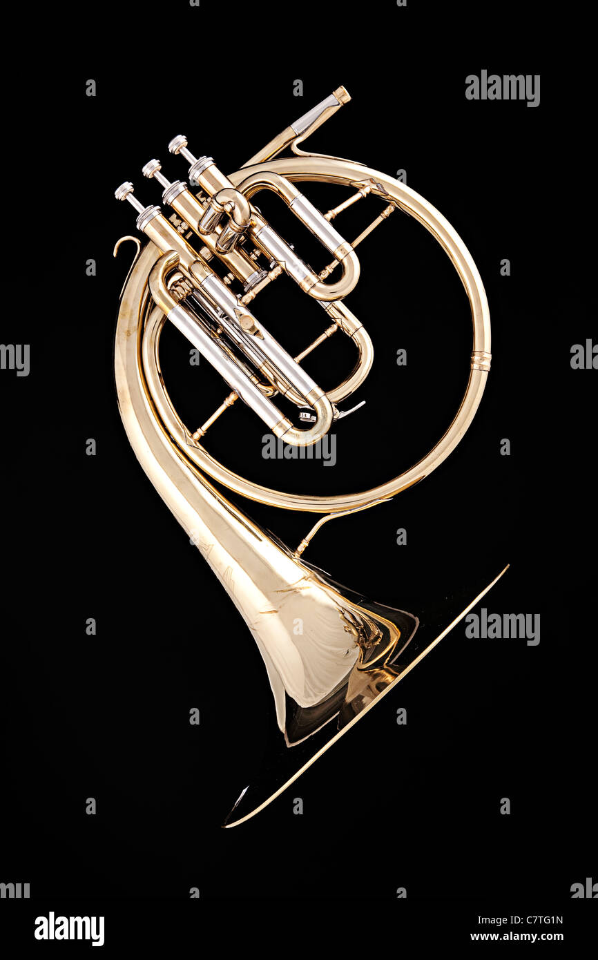 An antique gold French horn isolated against a black background Stock ...