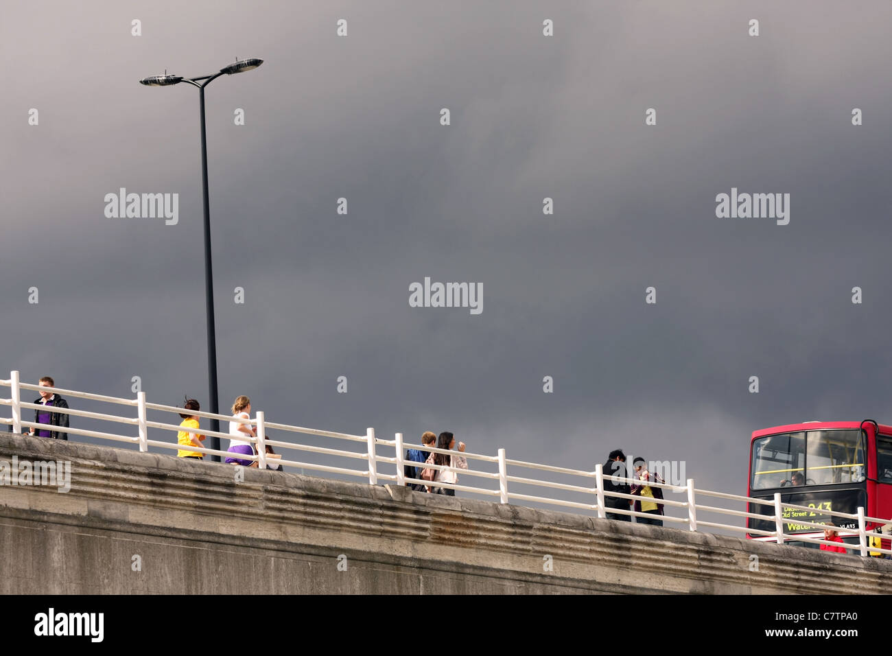 looking up at people crossing Waterloo Bridge, London, in sunshine but ...
