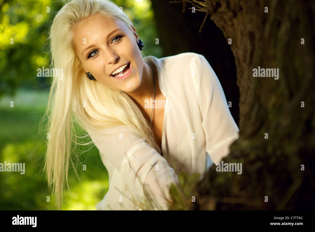 Pretty woman peeking behind tree hi-res stock photography and images ...