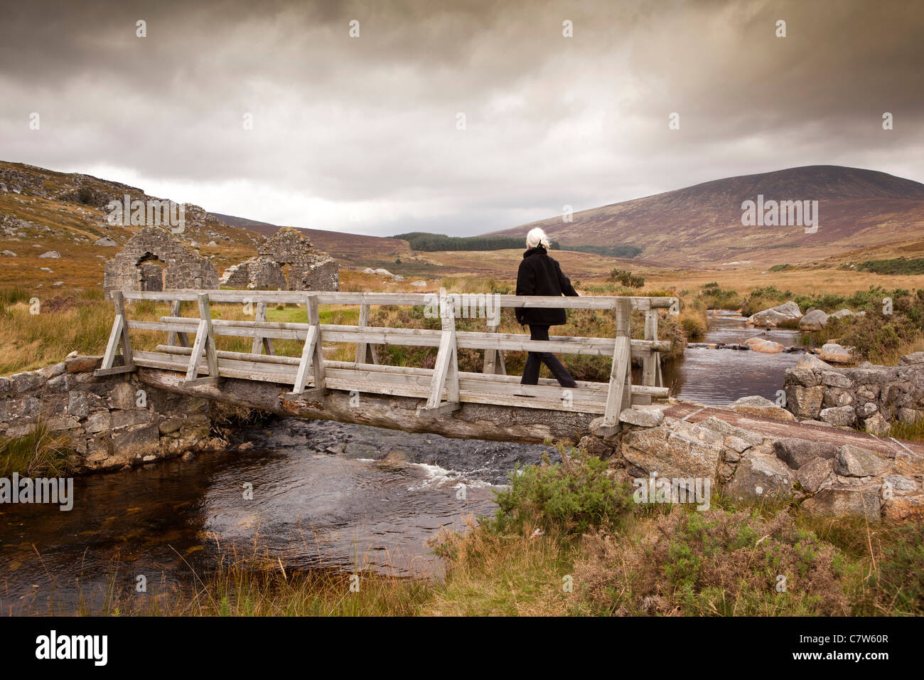 Ireland, Co Wicklow, Wicklow Mountains visitor crossing Avonmore River ...