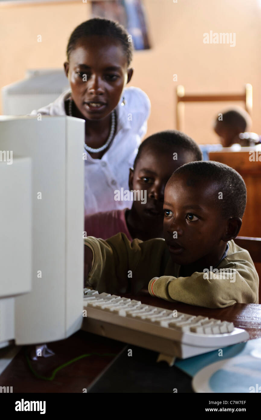 A teacher helping children during an introductory computer class ...