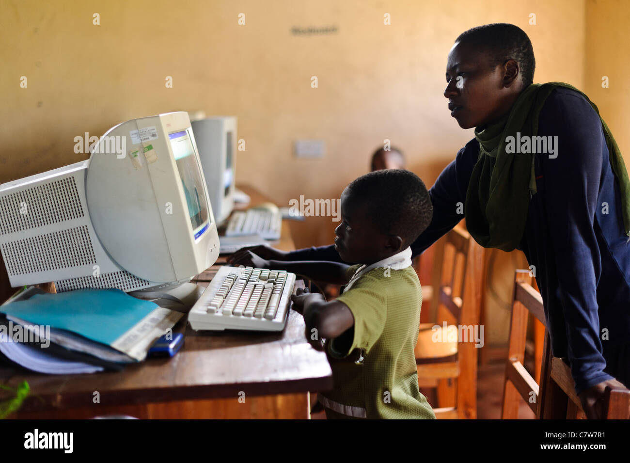A teacher helping children during an introductory computer class ...