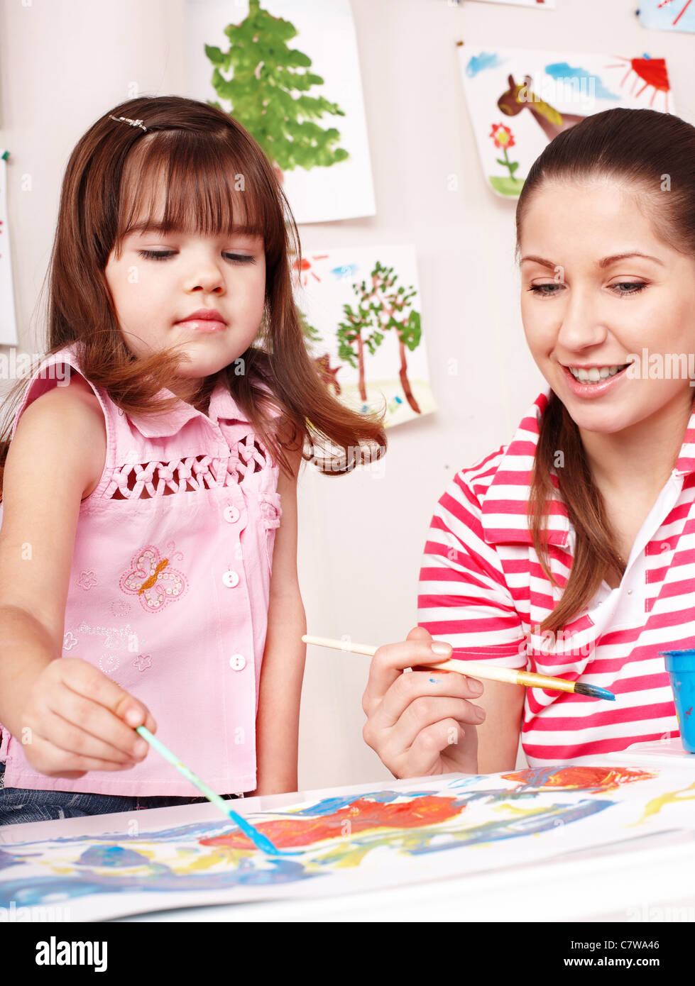 Child with teacher draw paints in play room Stock Photo - Alamy