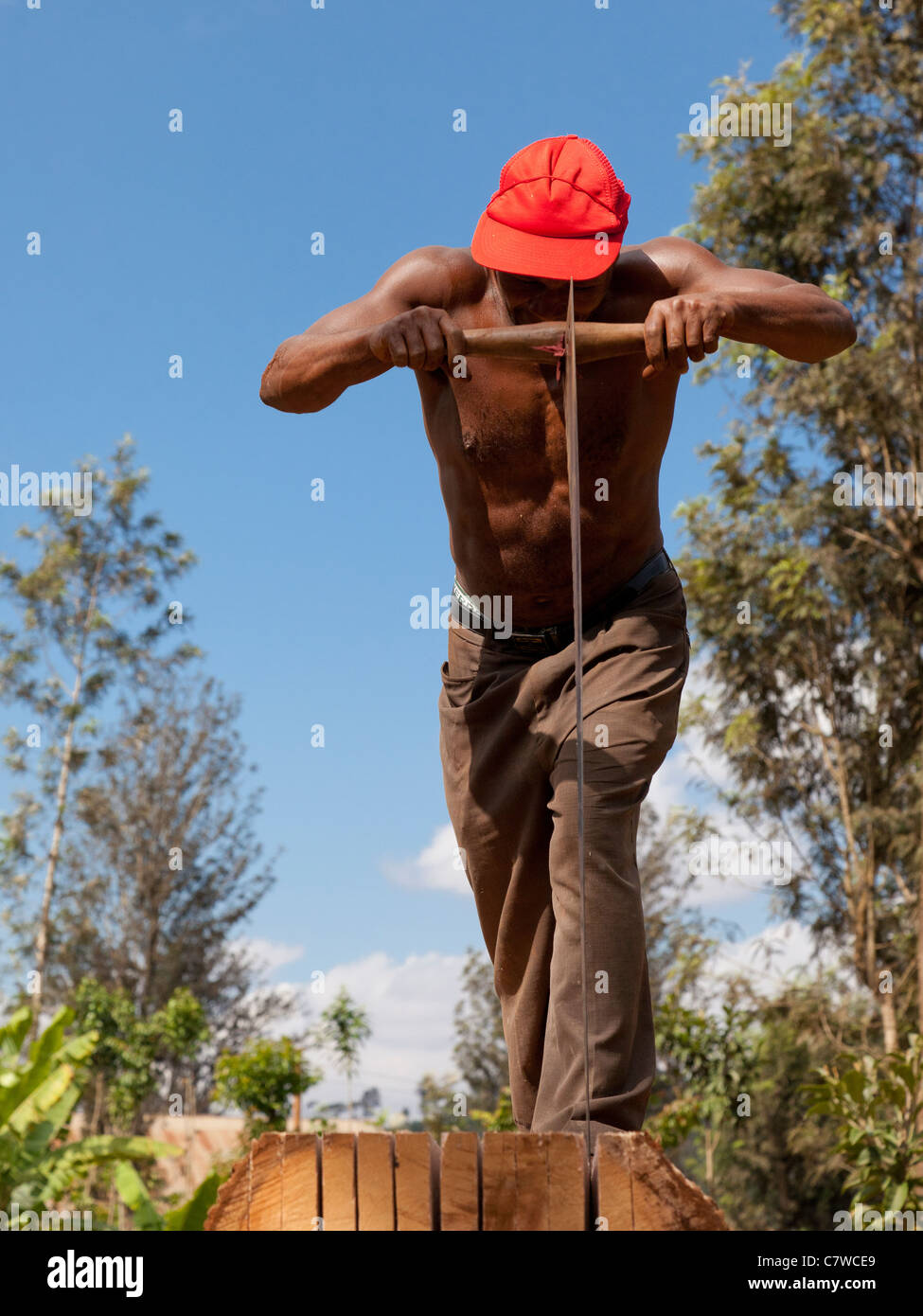 African man pit sawing a log to make timber, Mwika, Moshi, Tanzania ...