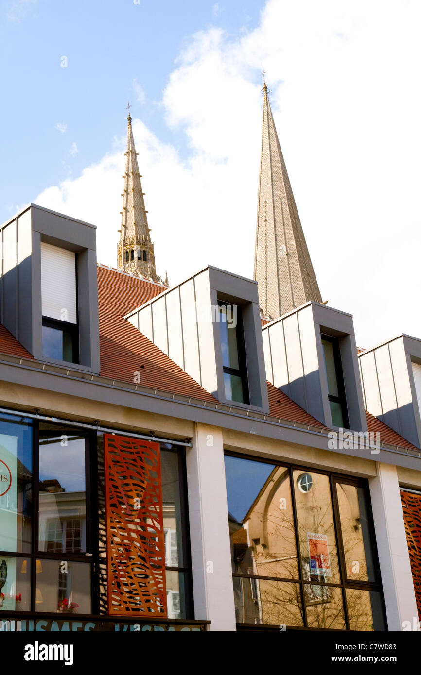 Modern building with twin spires of Chartres Cathedral towering above ...