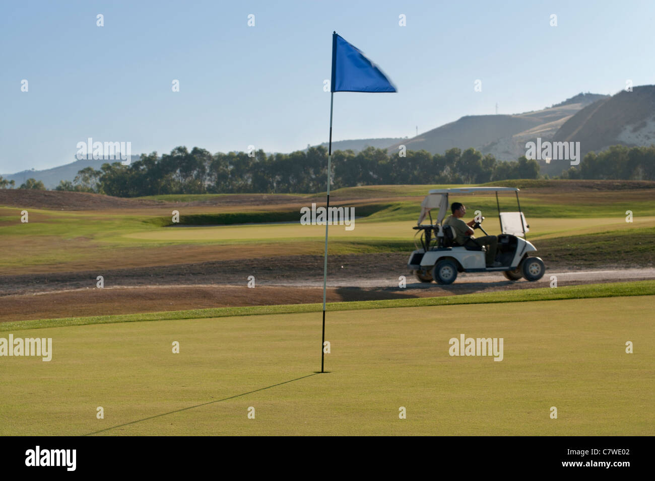 Golf buggy passing a golf green with a blue flag Stock Photo - Alamy