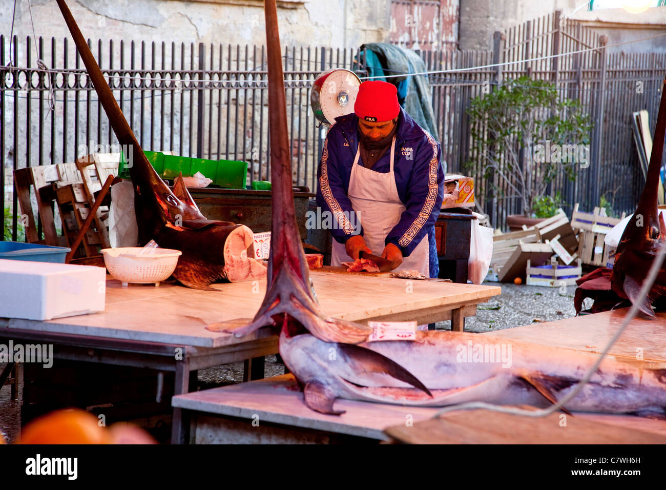 Man cutting slices of swordfish, traditional fish shop selling seafood ...