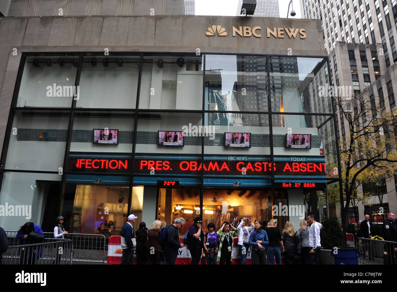 Small crowd standing in front glass windows red ticker tape news, NBC ...