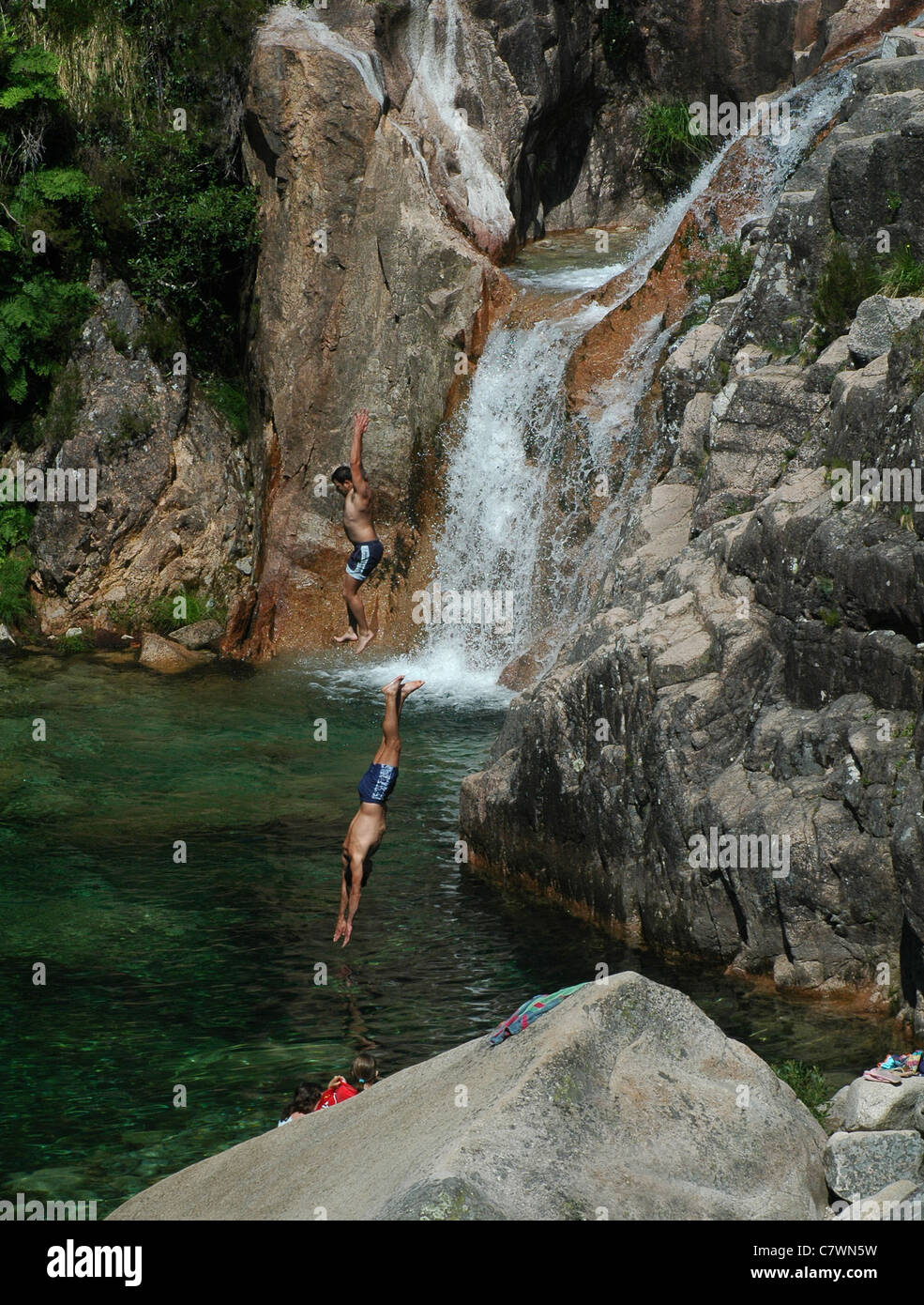 Vacationers jumping into the water at a waterfall in National Park ...