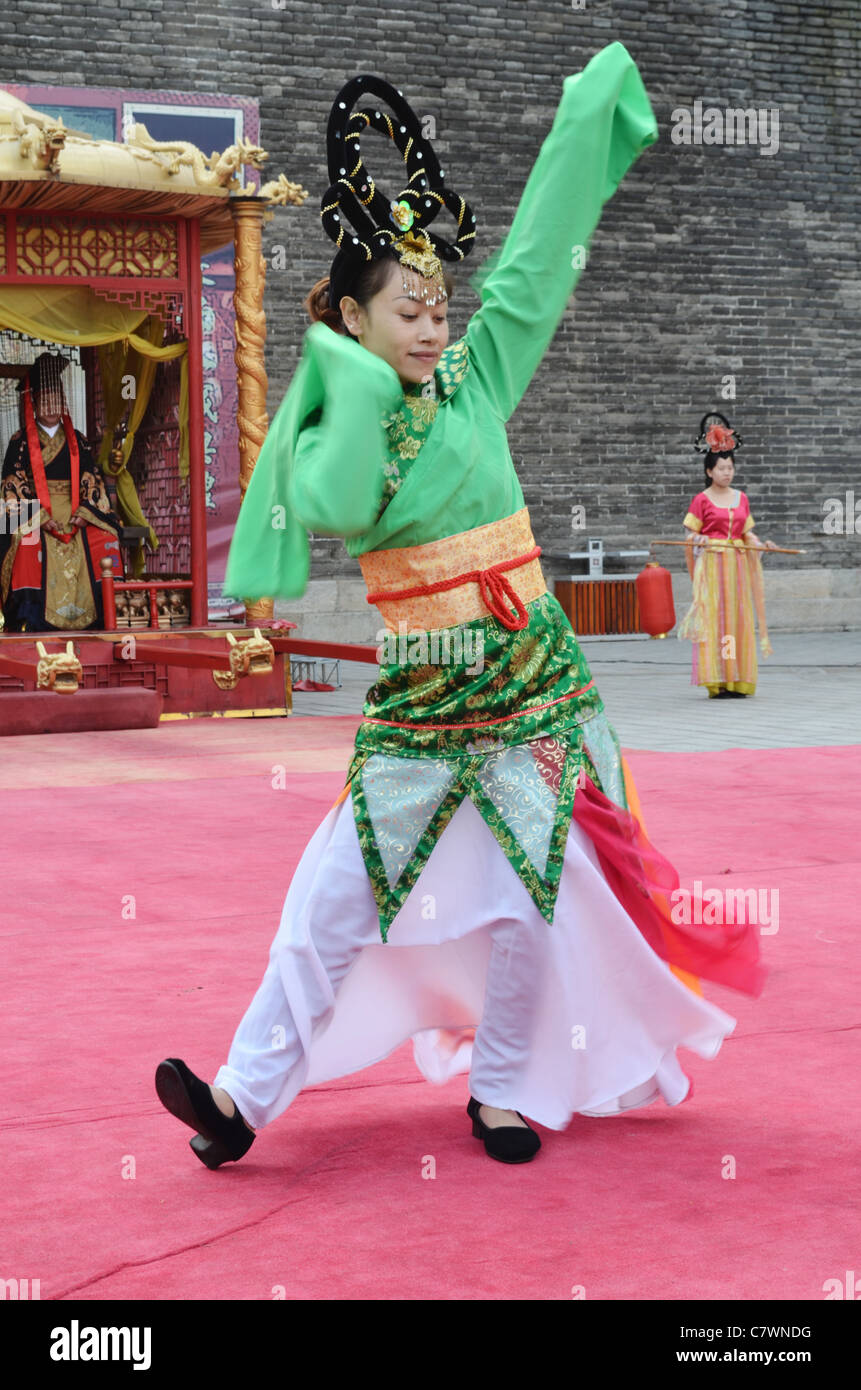 A dancer in traditional costume performs besides the city walls of Xi ...