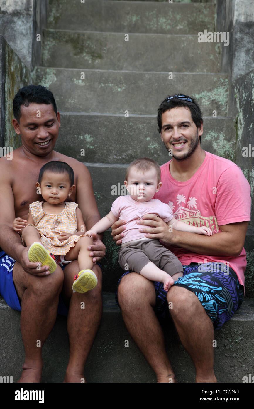 Balinese man and tourist with their baby daughters. Ubud, Bali ...