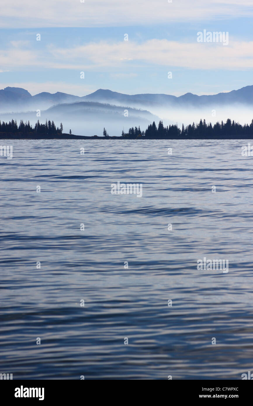A view across a lake looking at a distant shoreline with forest and ...