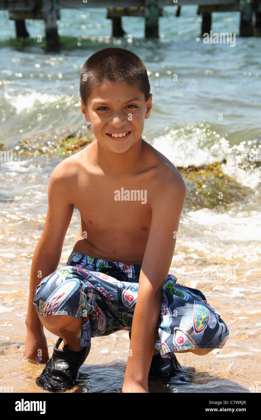 Hispanic boy on beach pose for portrait smiling squat in water Stock ...