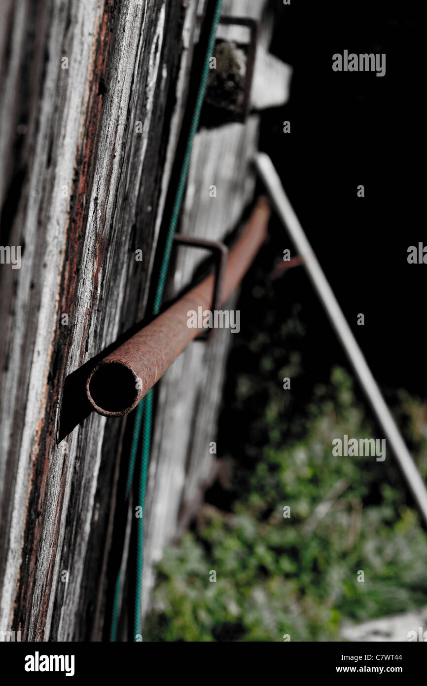 A rusty pole held up against a old metal shack Stock Photo - Alamy