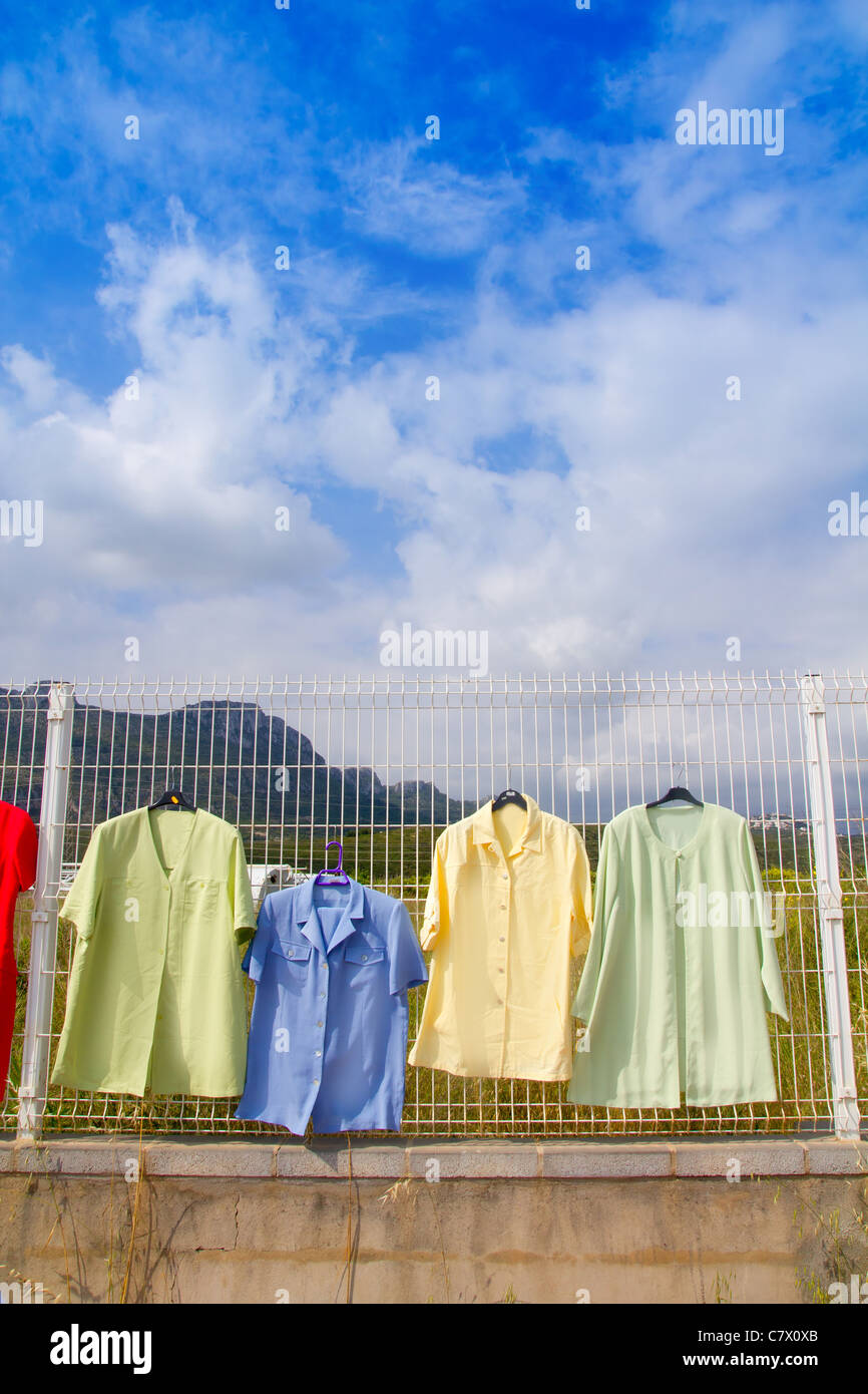 fashion outdoor market with clothes hanging from fence under blue sky ...