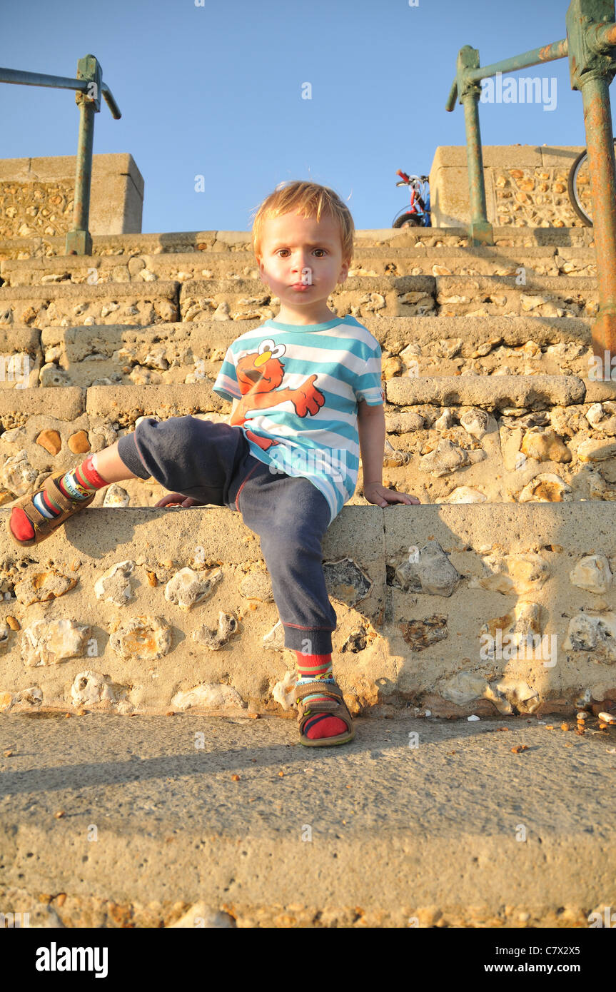 A little toddler boy sitting on stone beach stairs Stock Photo - Alamy